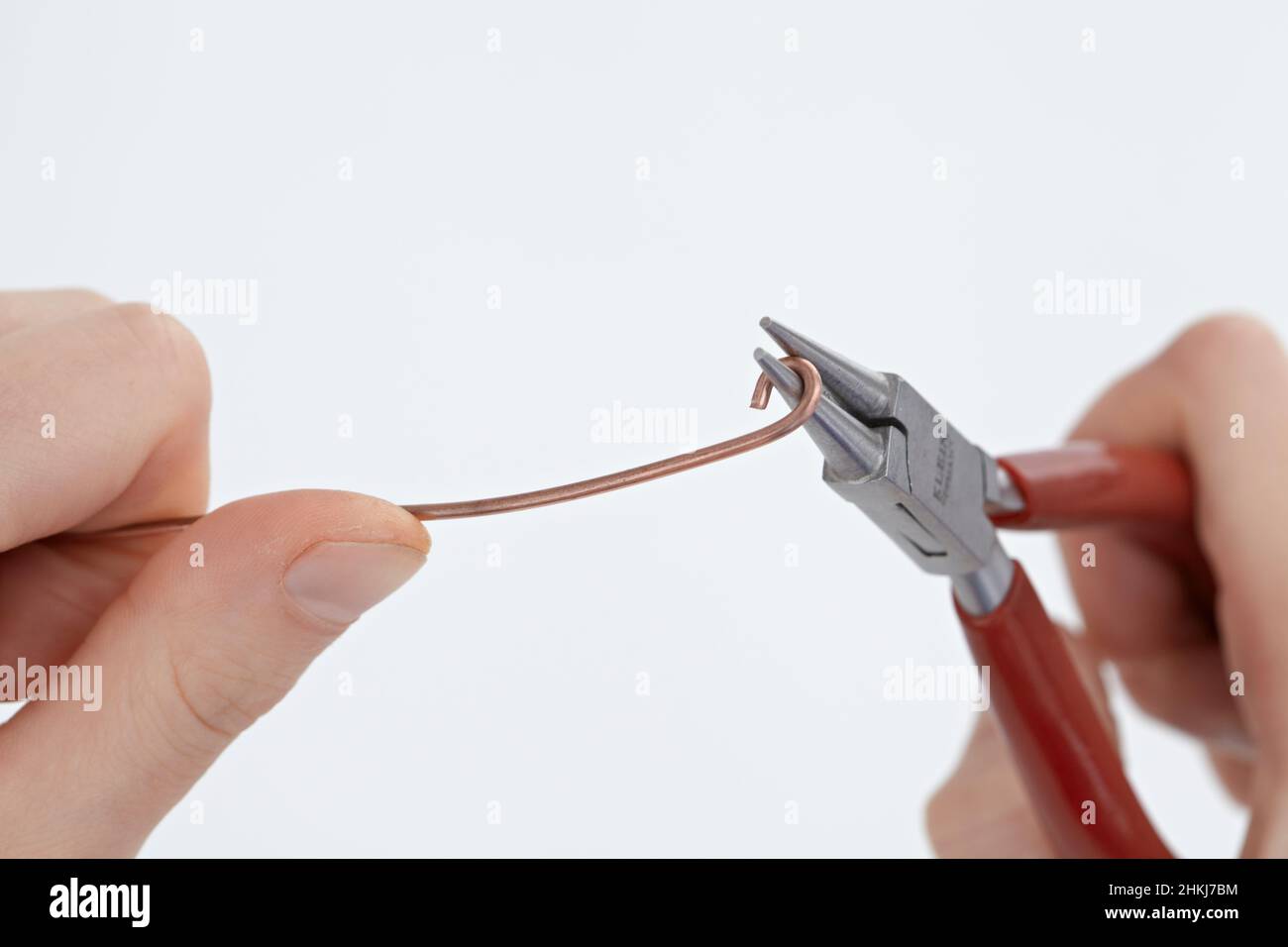 Using round-nosed pliers to make tiny loop at end of wire Stock Photo ...