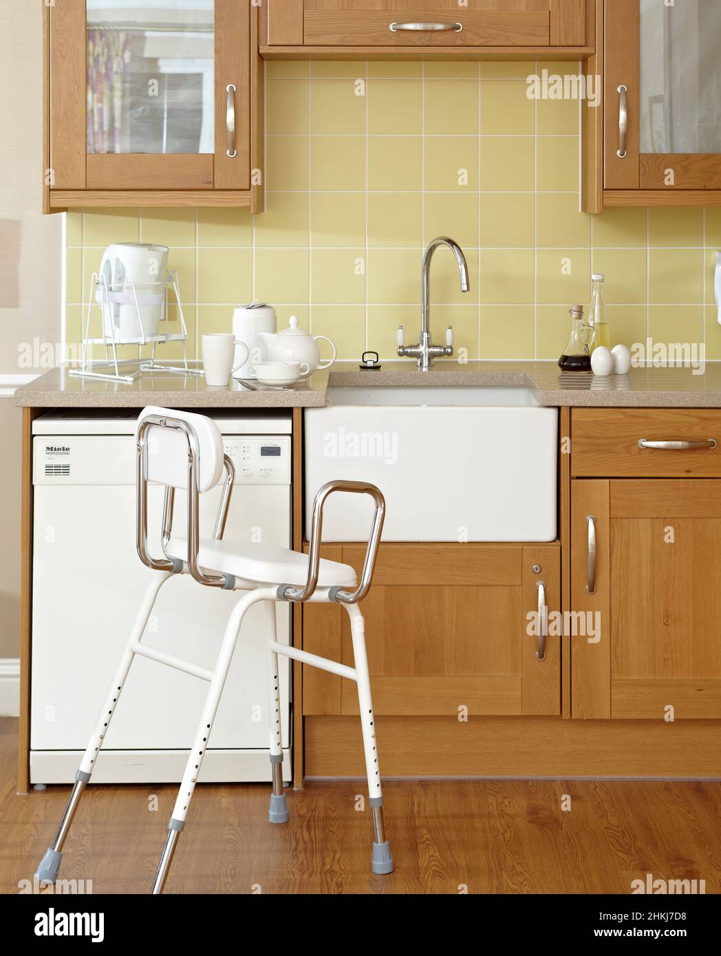 Using a chair or stool for washing at basin in kitchen Stock Photo - Alamy