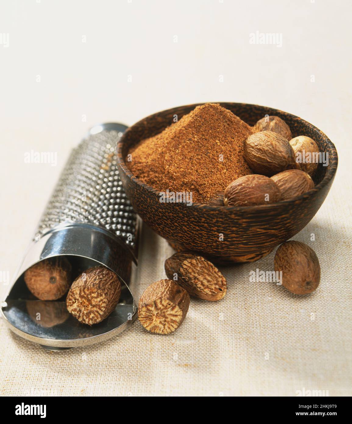 Whole nutmeg kernels and ground nutmeg in wooden bowl Stock Photo - Alamy