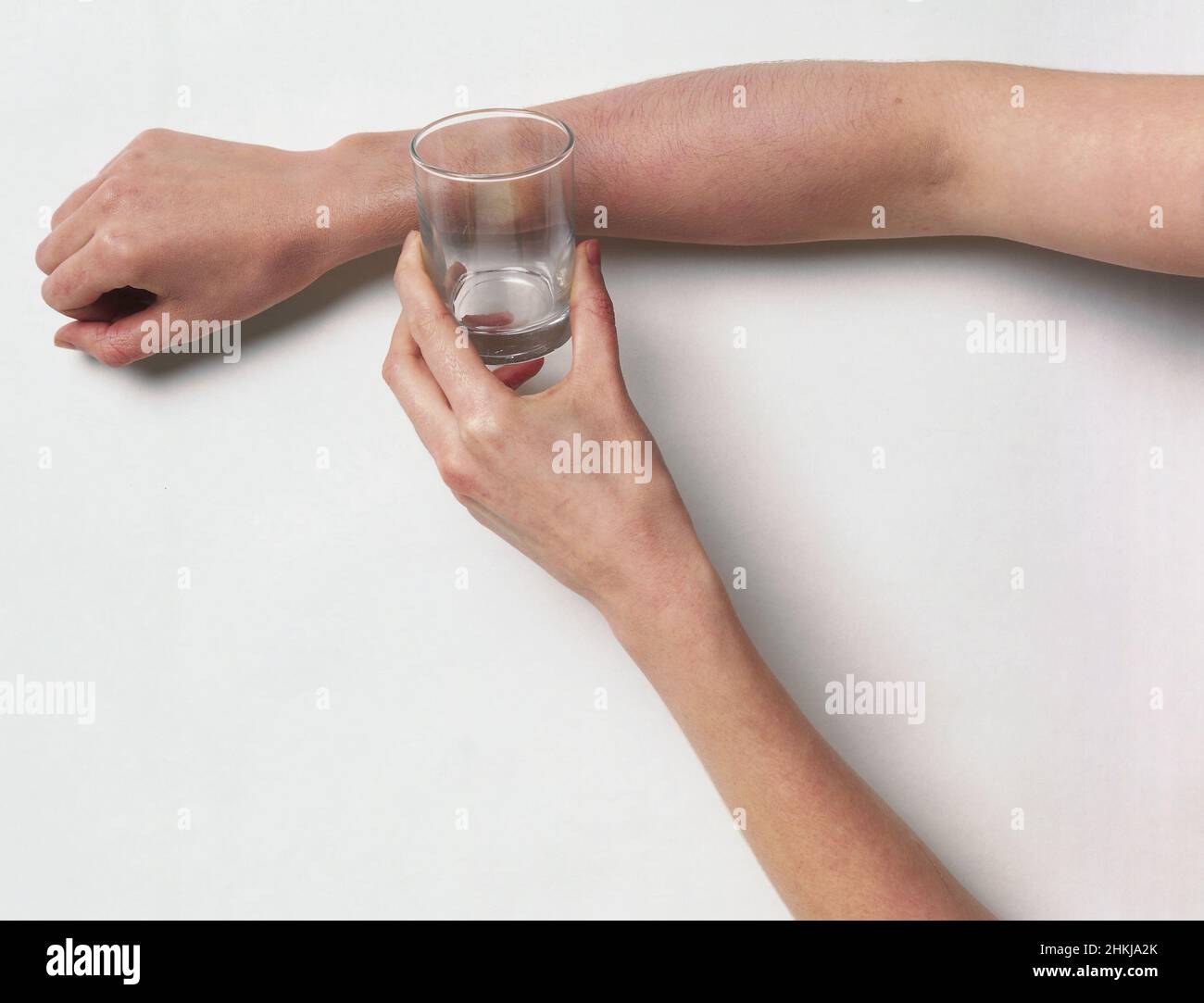 Person placing drinking glass next to their lower arm Stock Photo - Alamy