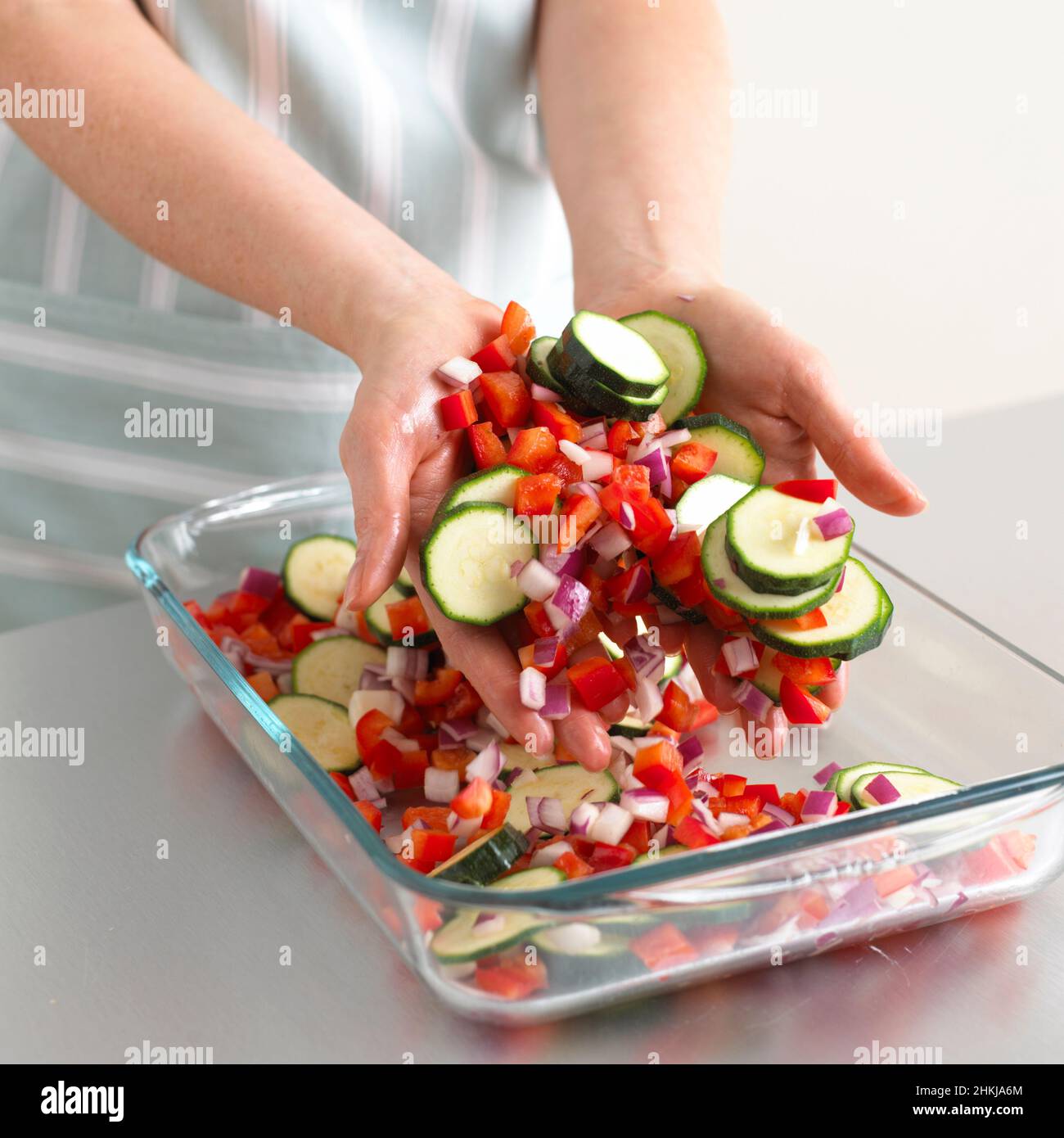 Putting vegetables in large glass oven-proof dish Stock Photo - Alamy