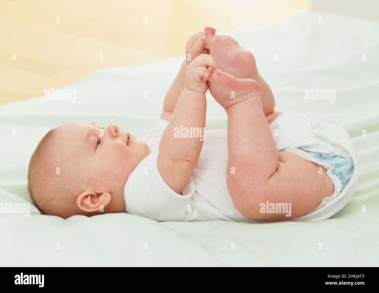 Baby lying on back and clutching toes with hands Stock Photo - Alamy