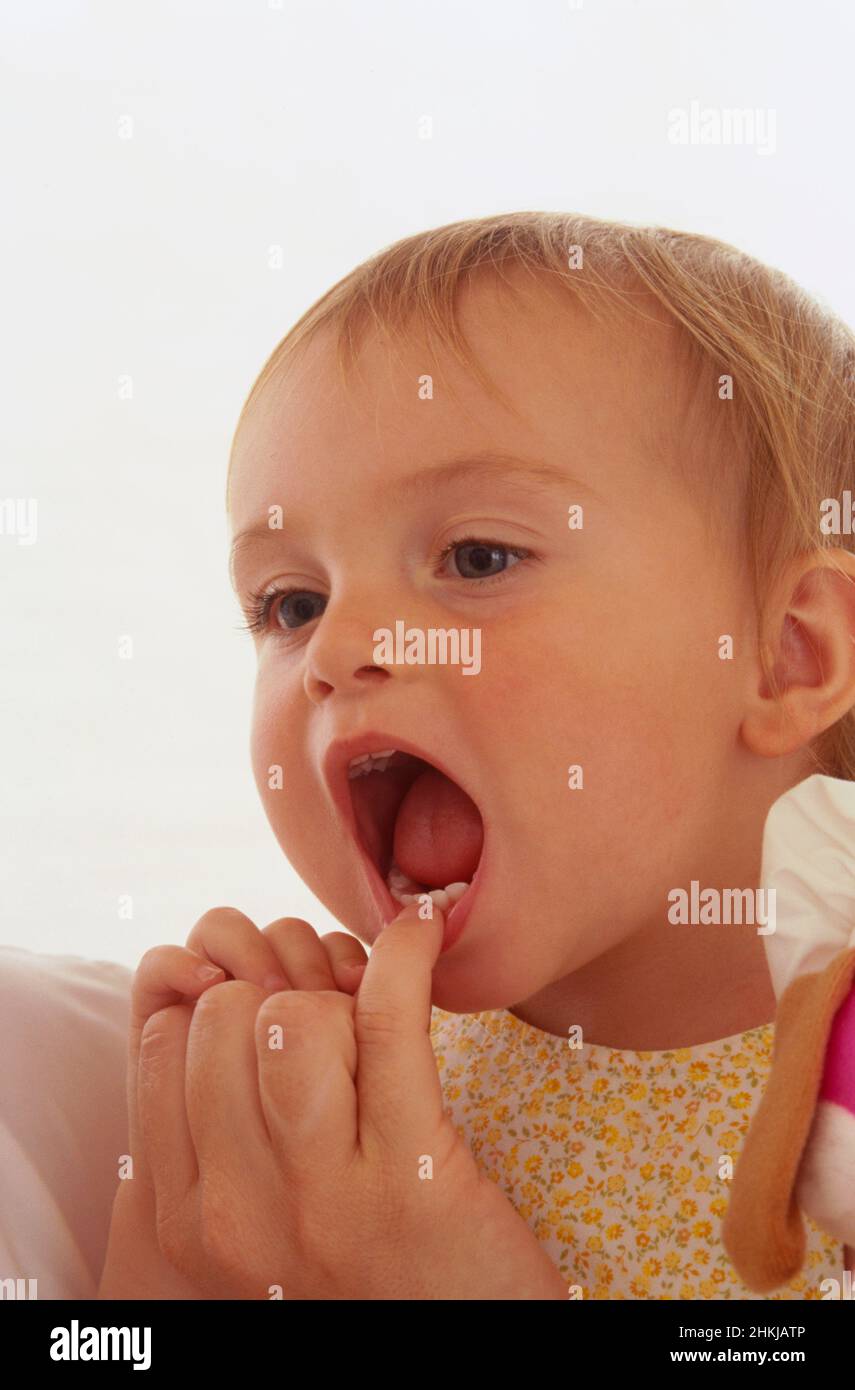 Hand pulling down bottom lip of toddler and checking teeth Stock Photo ...