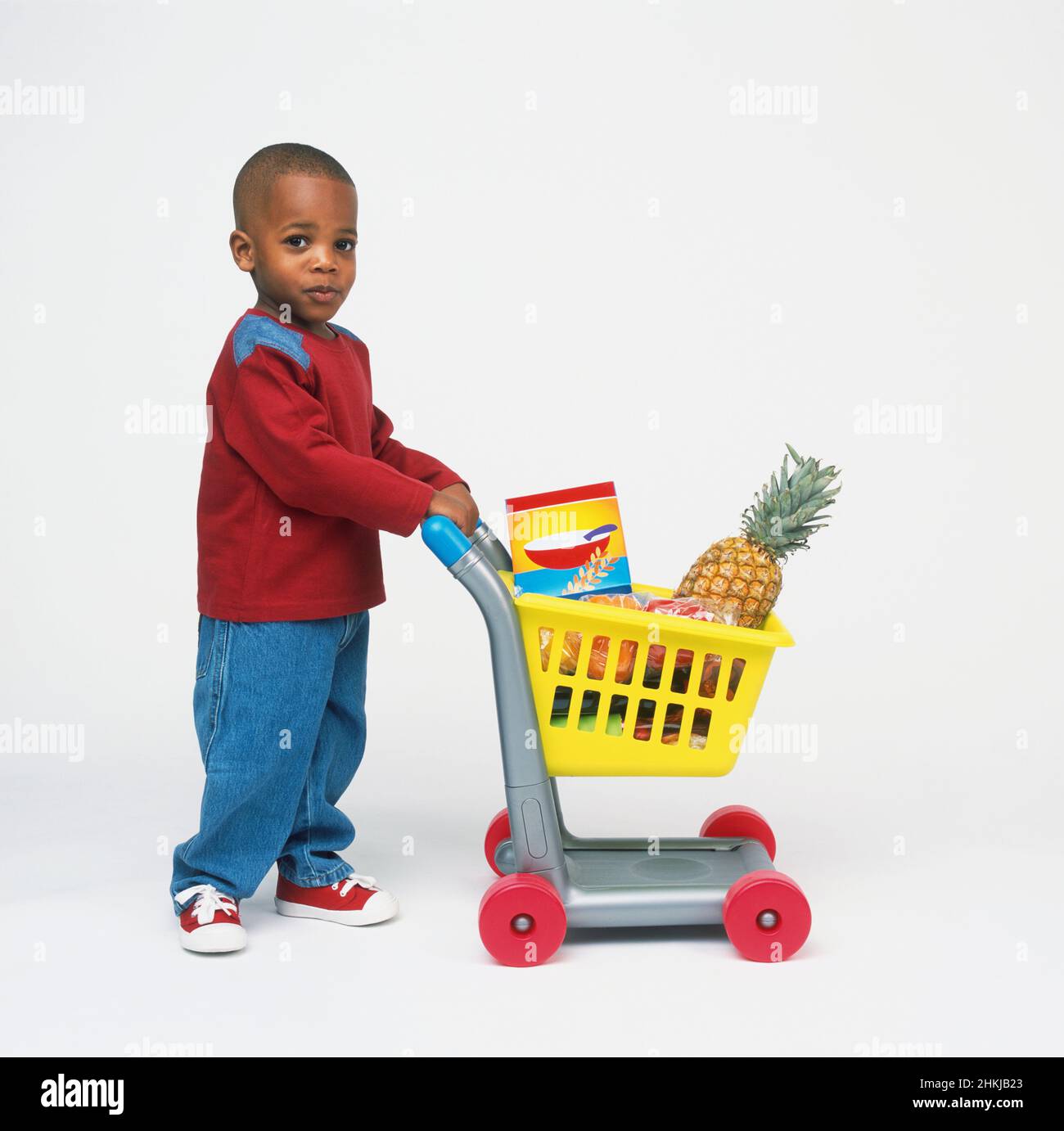 Child pushing a toy shopping trolley Stock Photo - Alamy