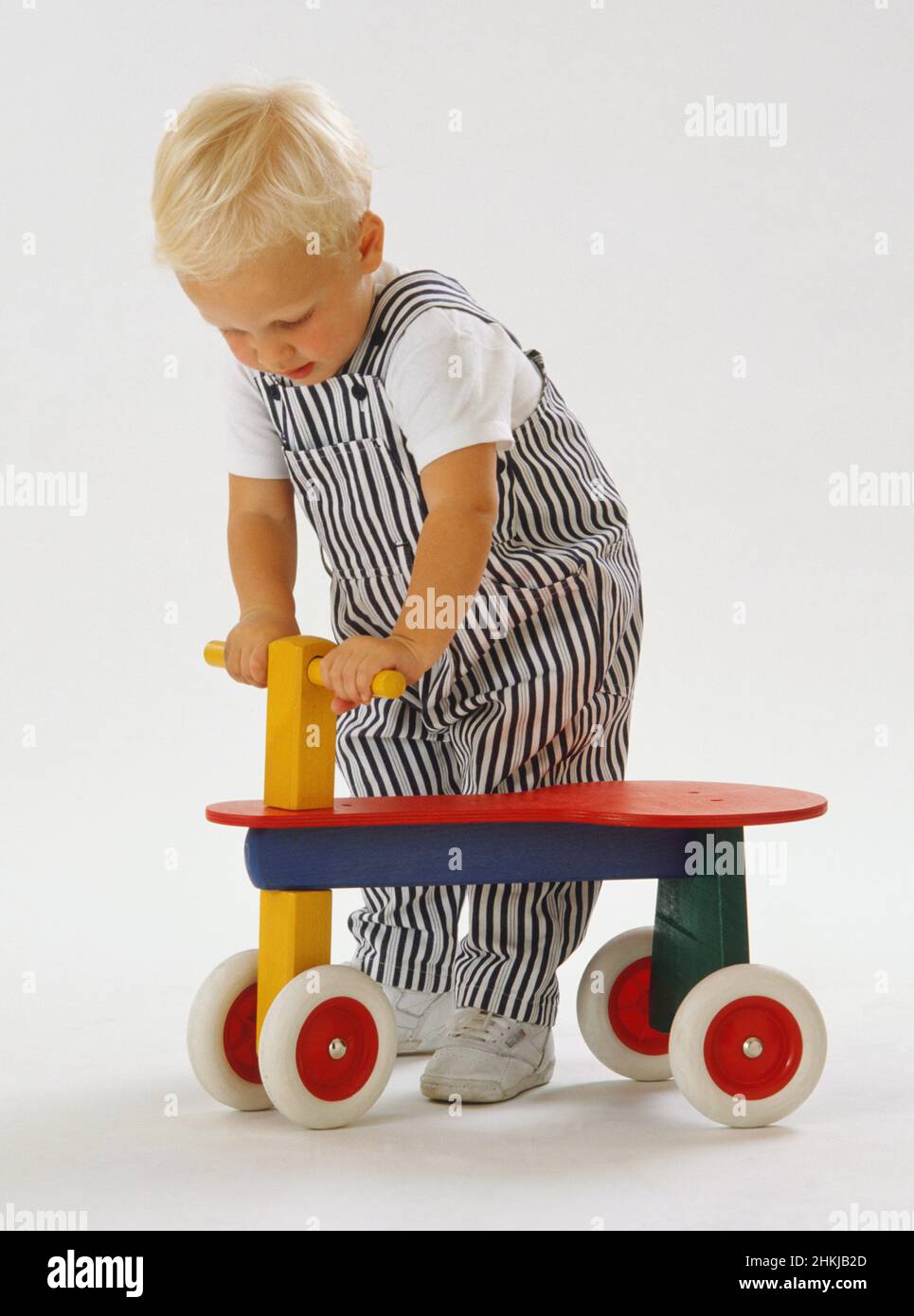 Toddler holding handlebars of wooden toy tricycle Stock Photo - Alamy