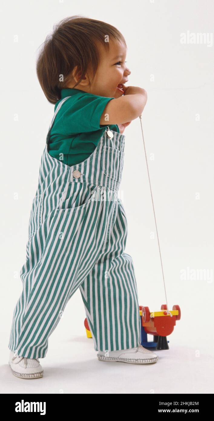 Toddler pulling toy train along on piece of string Stock Photo - Alamy