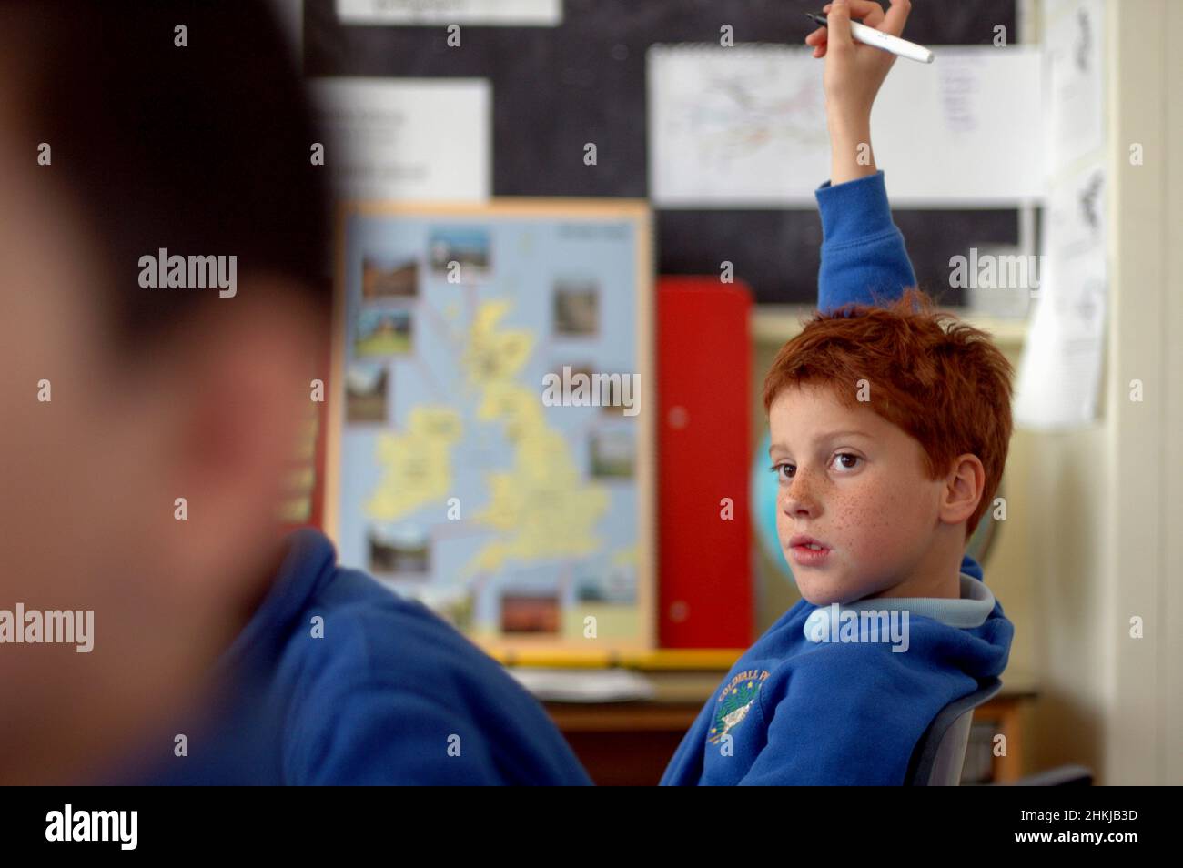 Two boys in classroom, one raising his hand Stock Photo - Alamy