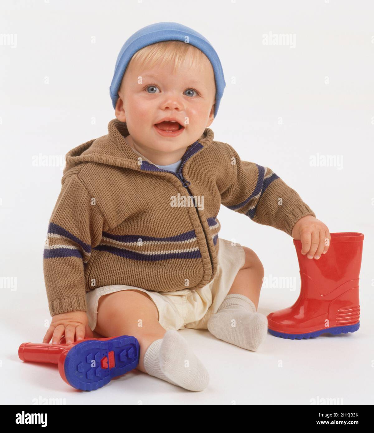 Boy sitting on the floor holding wellies Stock Photo - Alamy