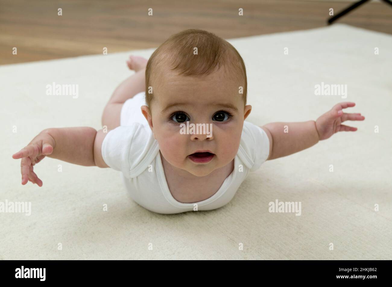 Baby girl lying on front, arms outstretched Stock Photo - Alamy