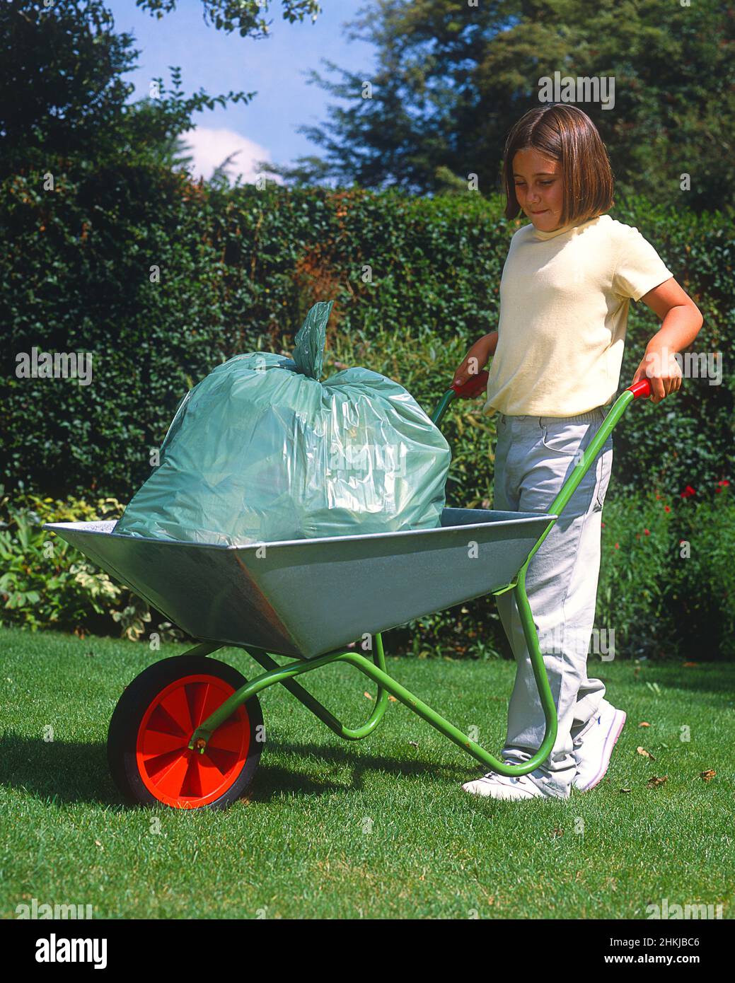 Girl carrying a full sack of rubbish on a wheelbarrow Stock Photo - Alamy