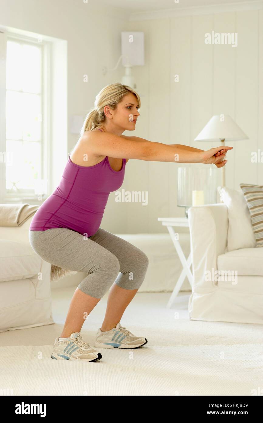 Pregnant woman in squatting with arms out front Stock Photo - Alamy
