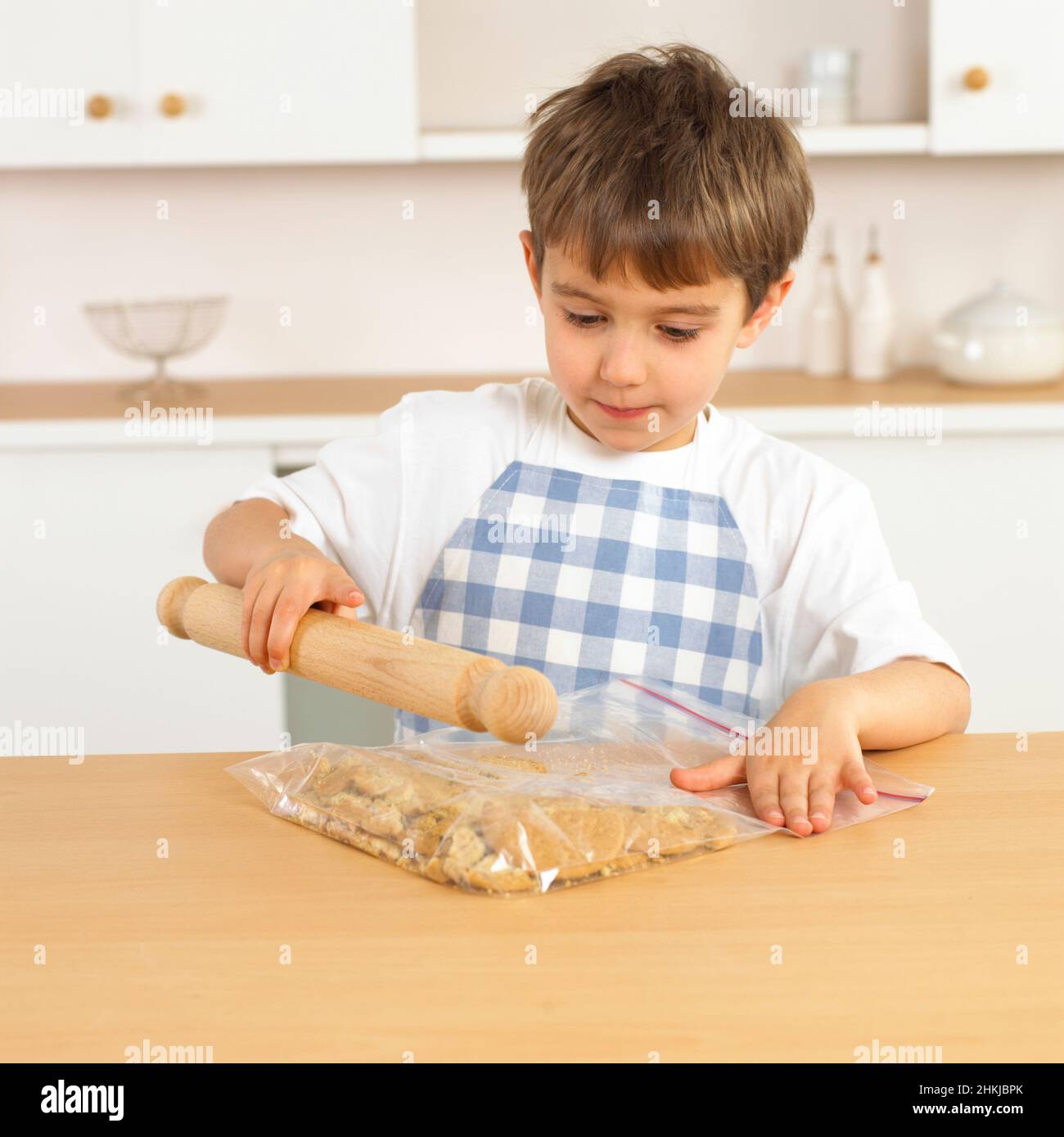 Boy holding rolling pin above bag of biscuits Stock Photo - Alamy