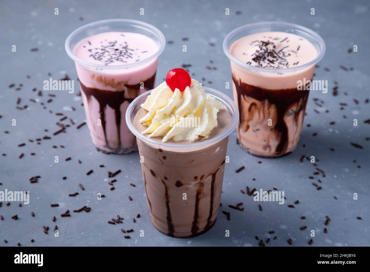 Three milkshakes with different flavors isolated on a gray table Stock ...