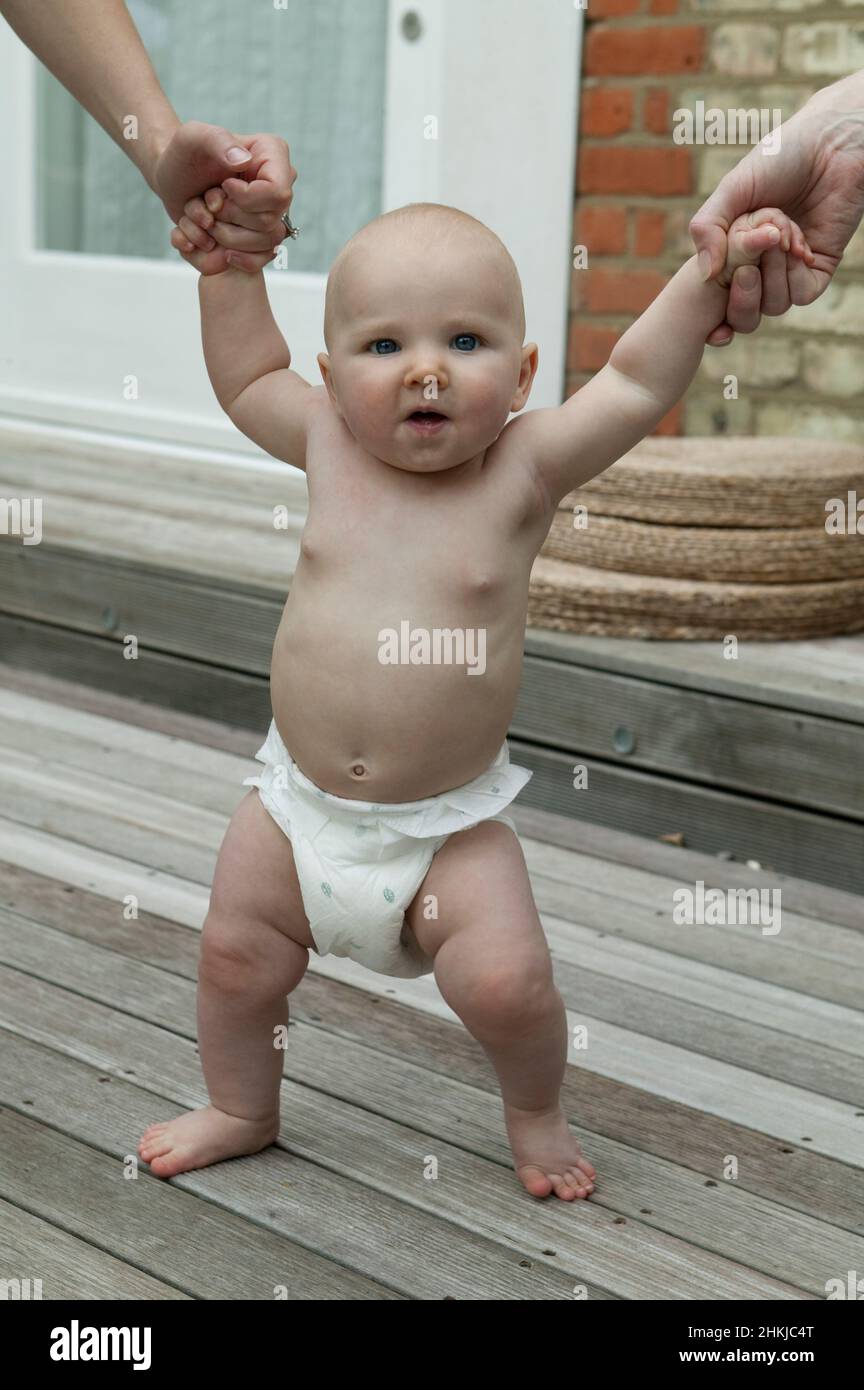 Baby boy being held upright to walk Stock Photo - Alamy