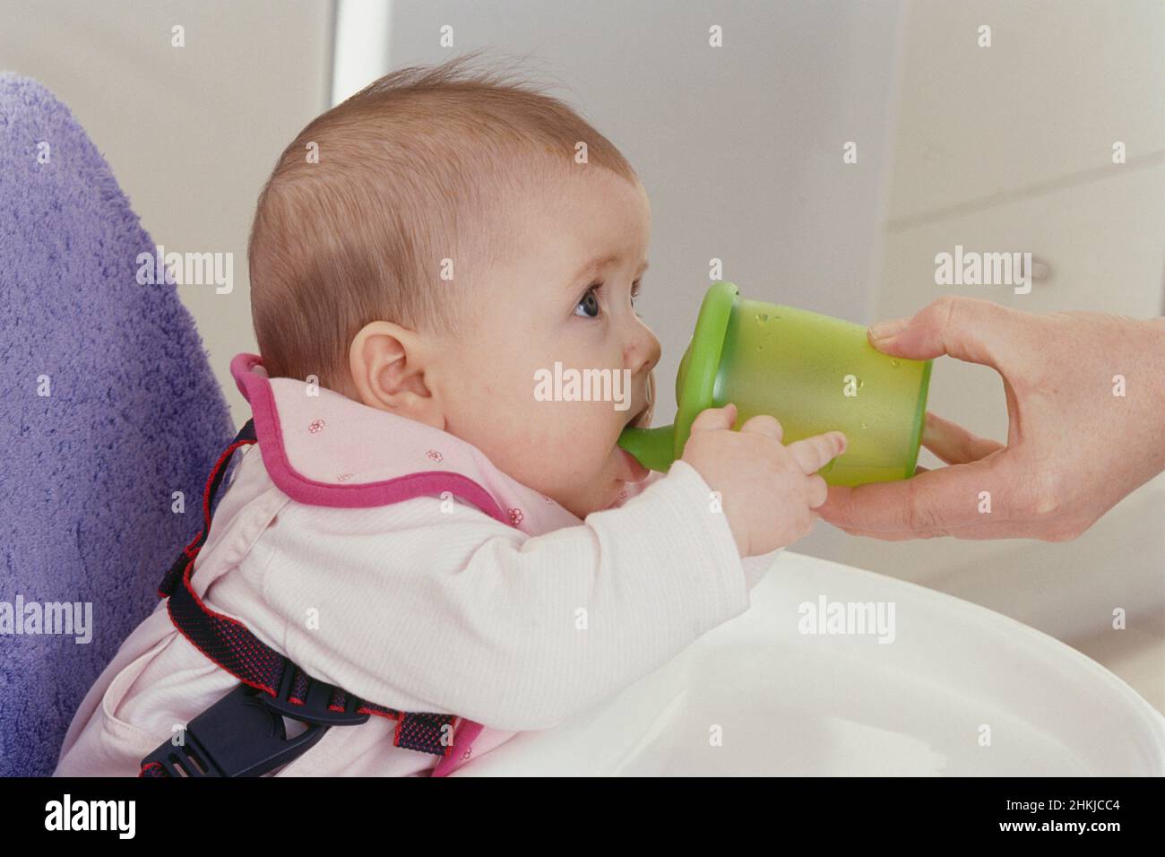 Green beaker held up to a baby's mouth Stock Photo - Alamy