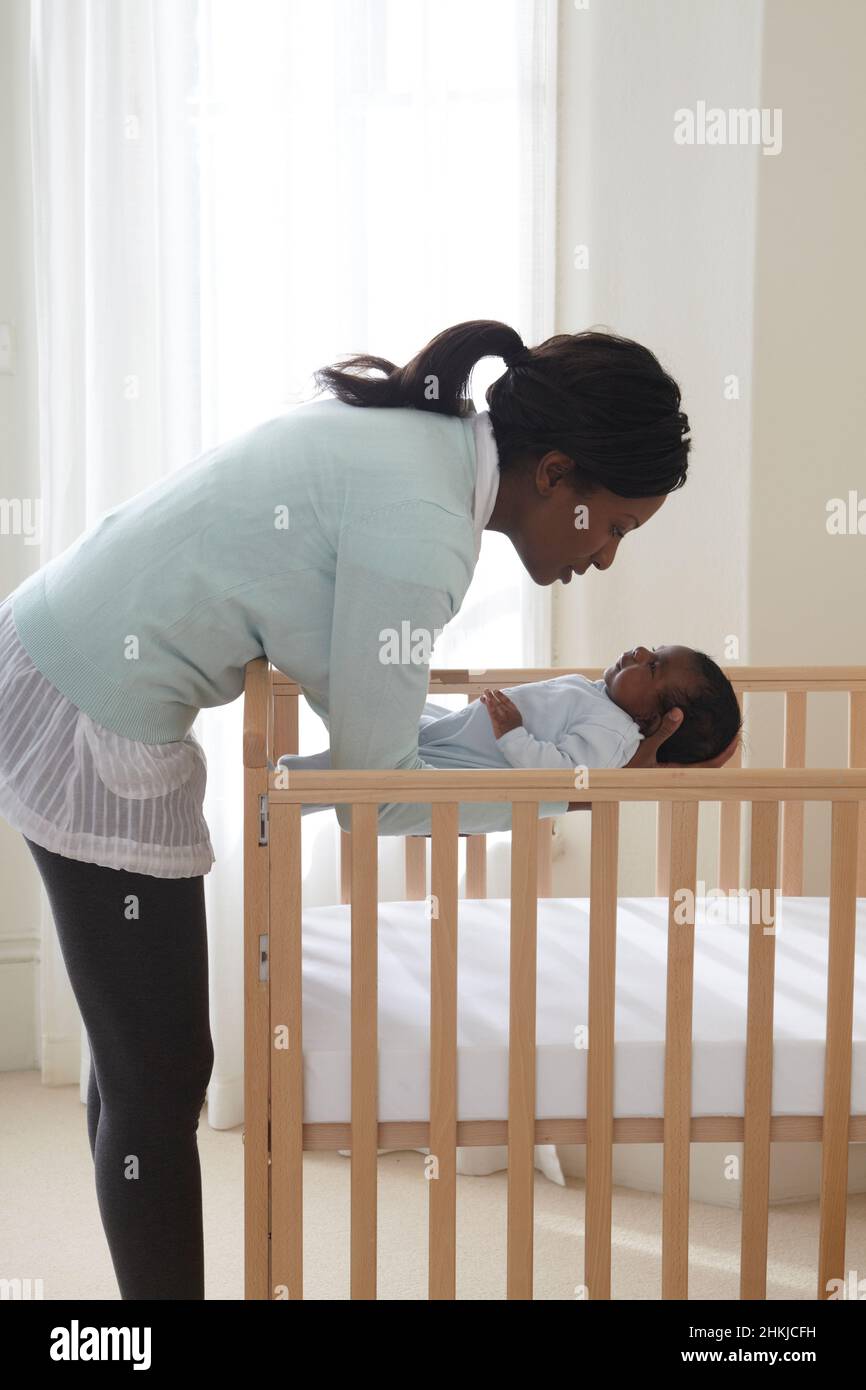 Woman holding baby boy above cot Stock Photo - Alamy