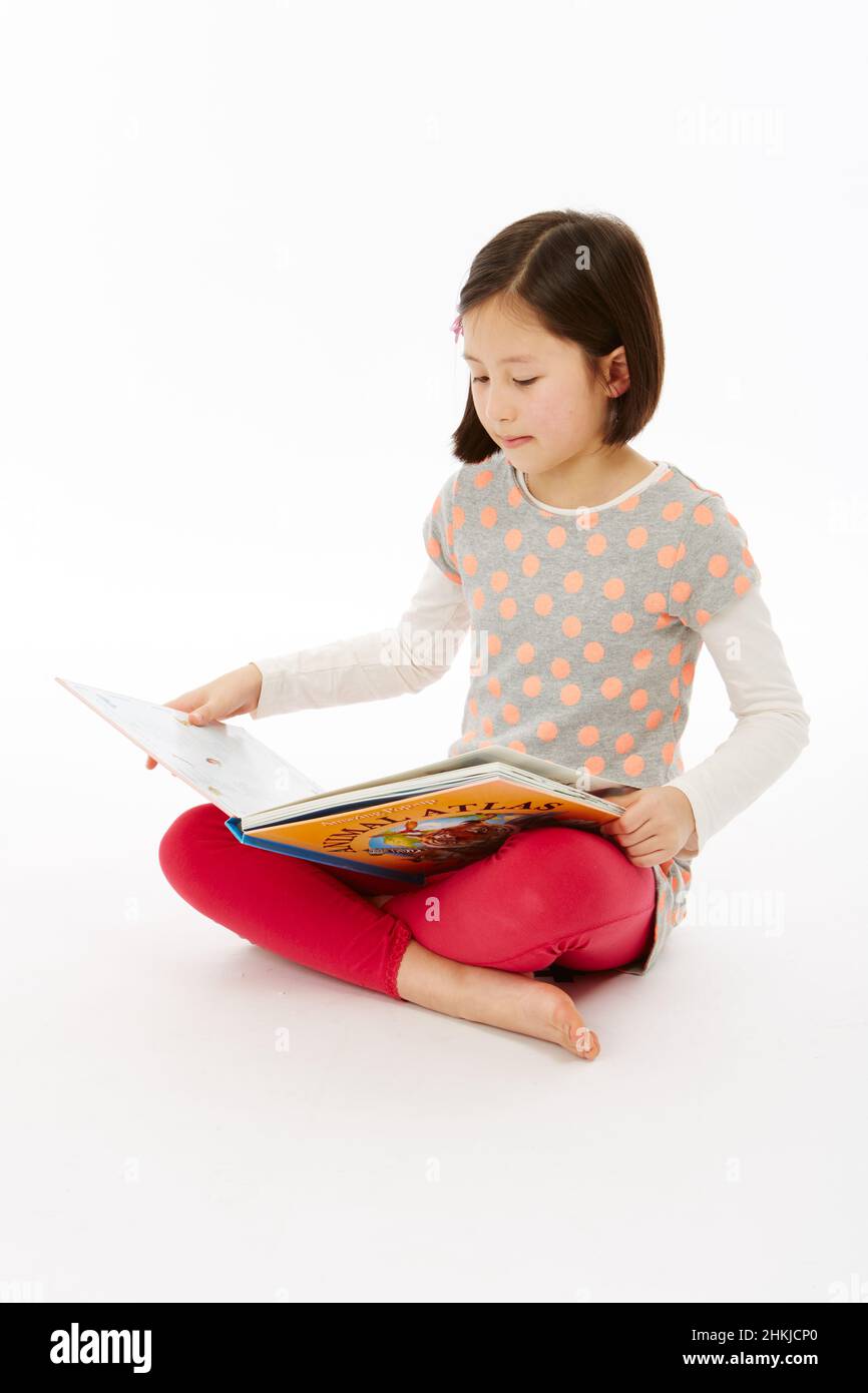 Girl sitting reading a book Stock Photo - Alamy