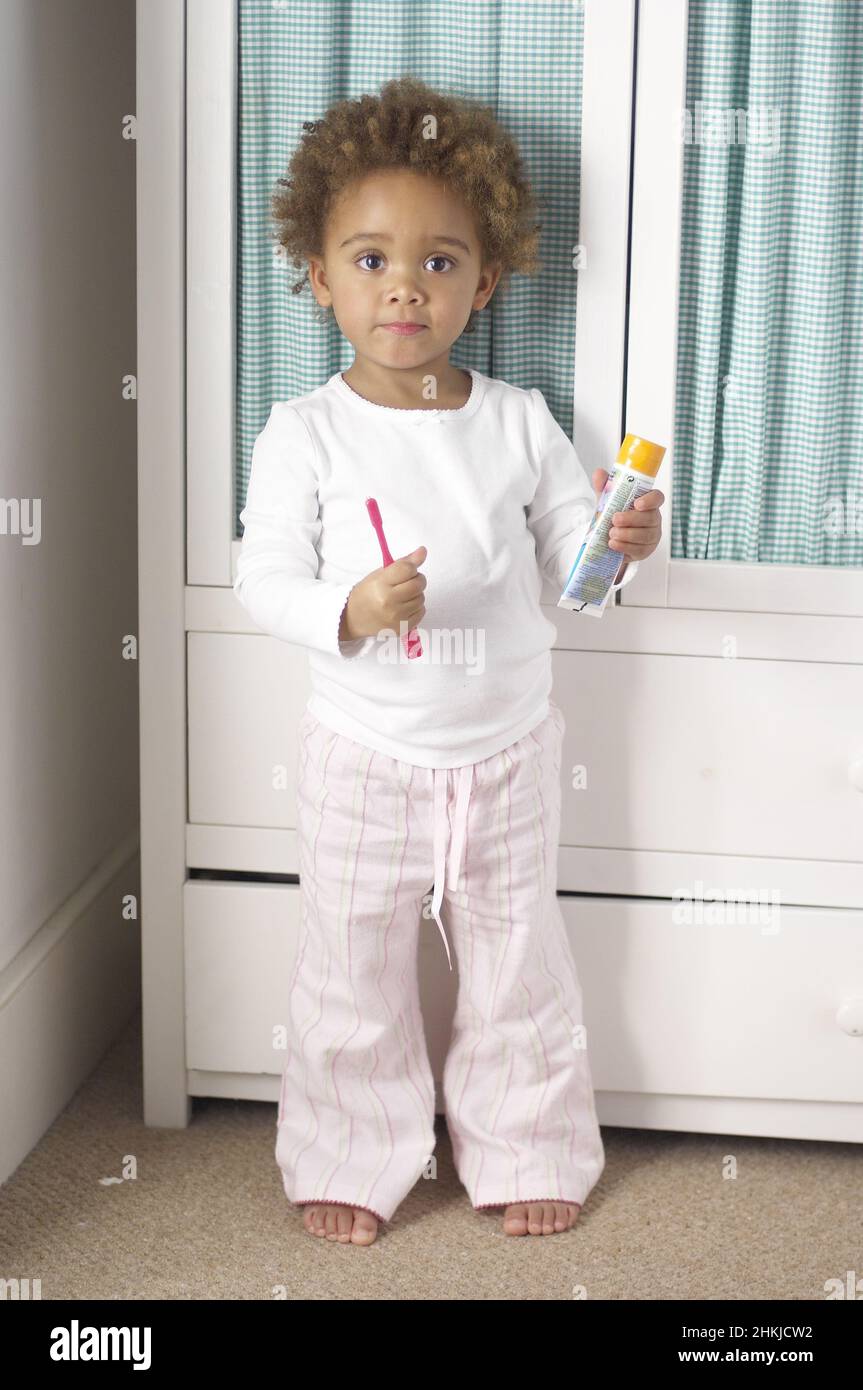 Toddler holding red toothbrush and tube of toothpaste Stock Photo - Alamy