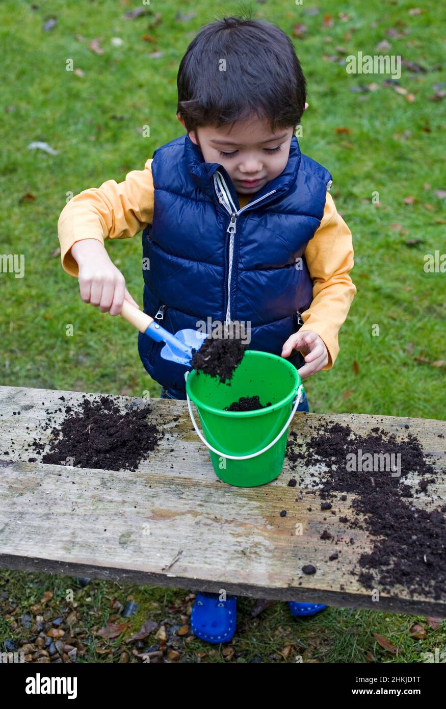 Boy holding trowel filled with compost above plastic bucket Stock Photo ...