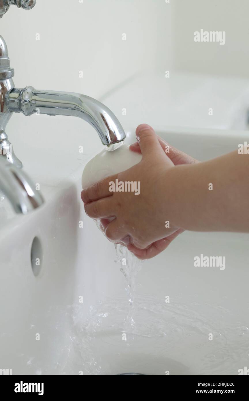 Baby girl washing her hands with soap in the sink Stock Photo - Alamy