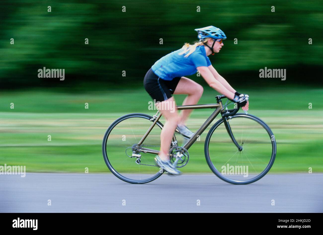 Young woman riding racing bicycle at speed on country road Stock Photo ...