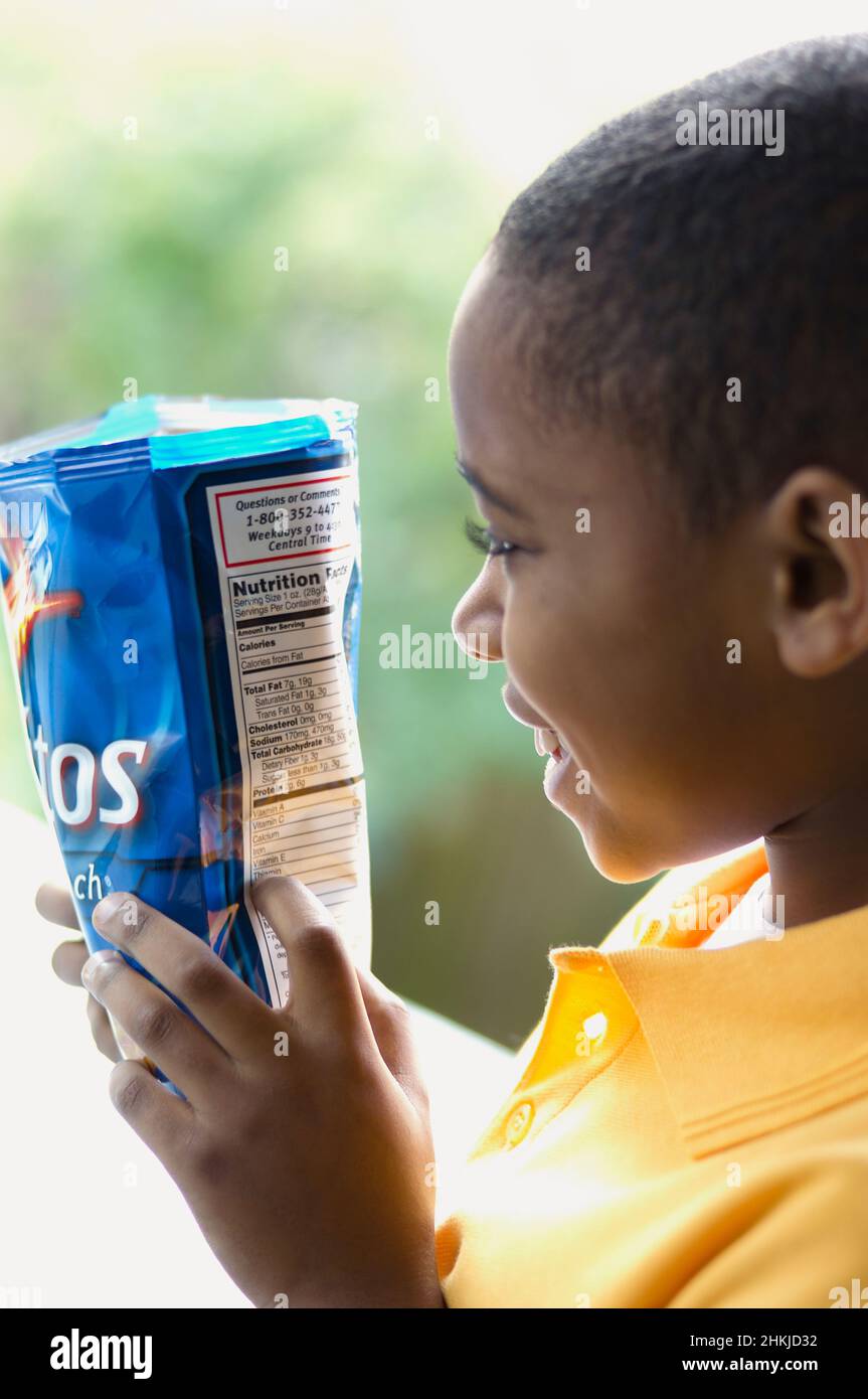 Boy reading ingredients on the back of savoury snacks Stock Photo - Alamy