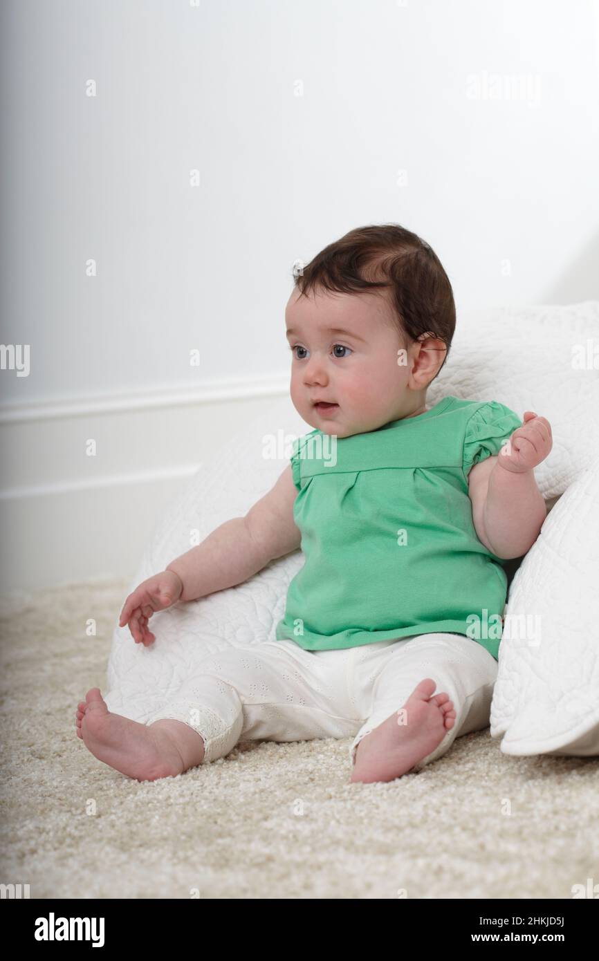 Baby girl supported by cushions Stock Photo - Alamy
