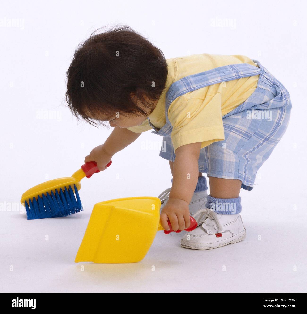 Toddler bending over to sweep floor with dustpan and brush Stock Photo ...