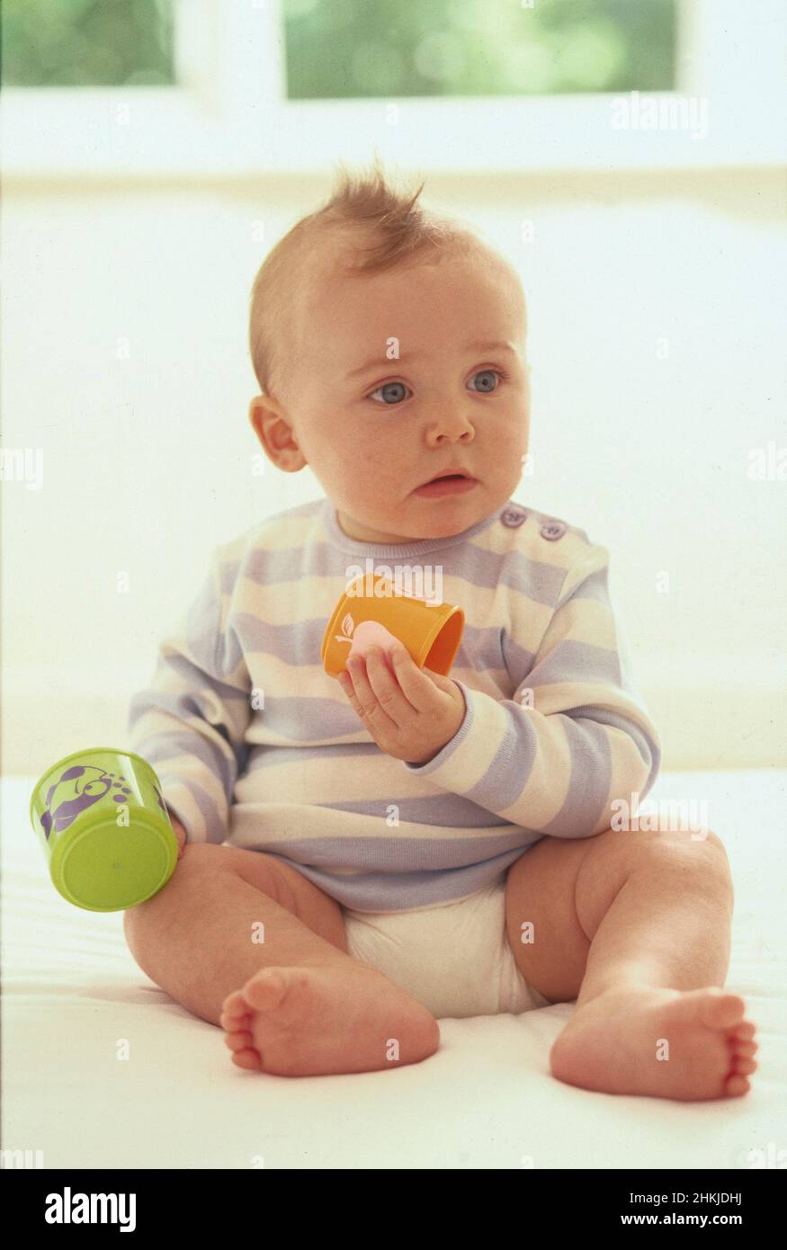 Baby sat holding cups Stock Photo - Alamy