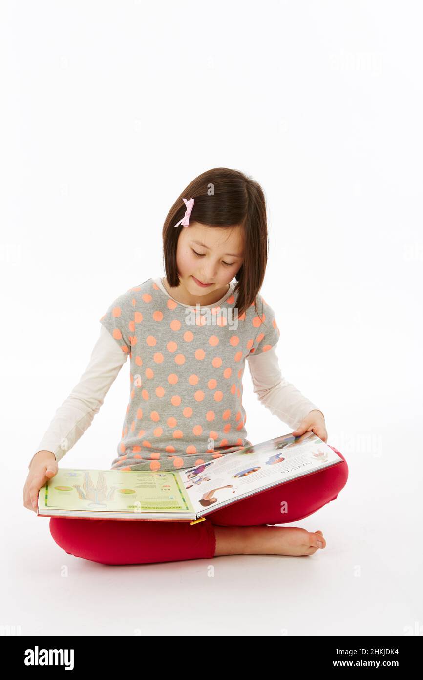 Girl sitting reading a book Stock Photo - Alamy