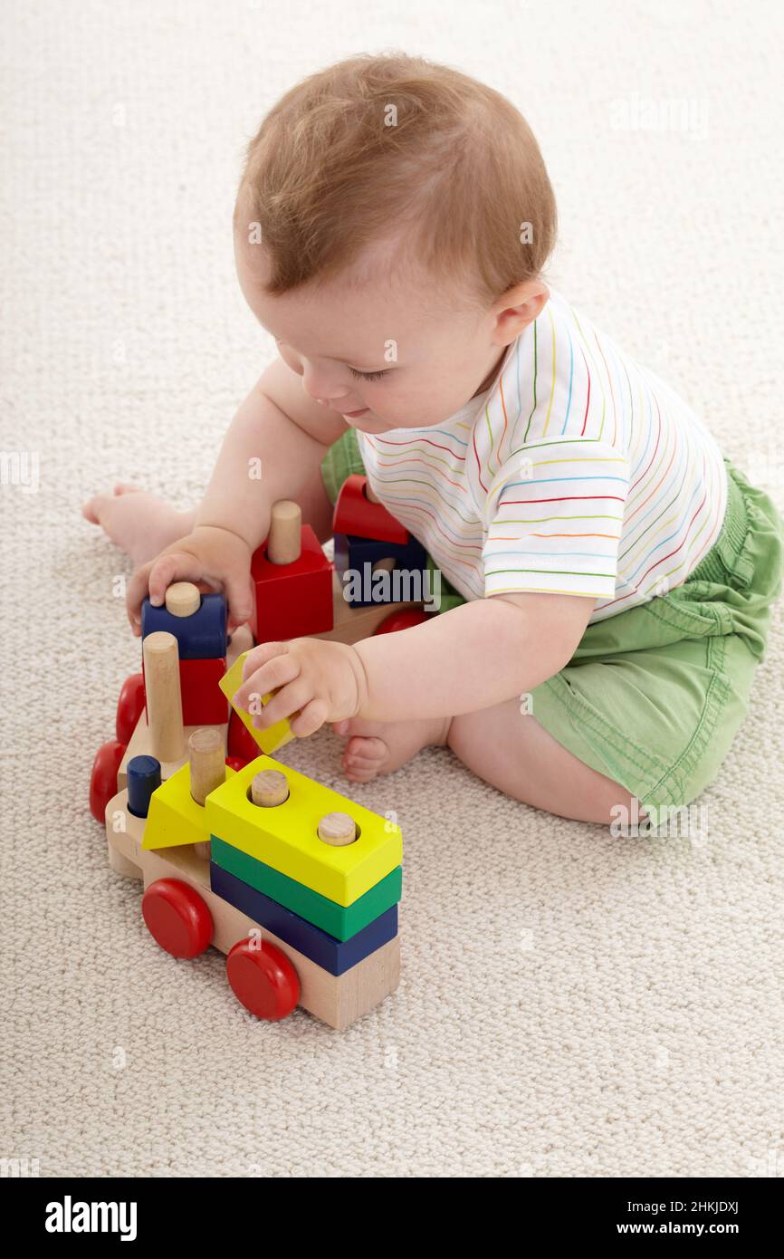 Baby boy playing with wooden train set Stock Photo - Alamy