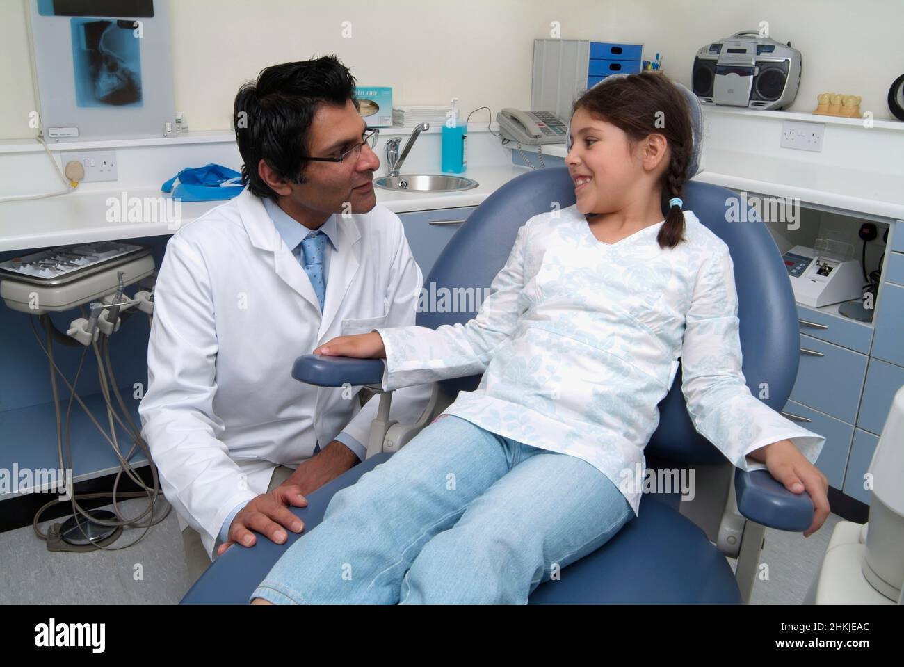 Dentist crouching beside girl in dentist's chair Stock Photo - Alamy