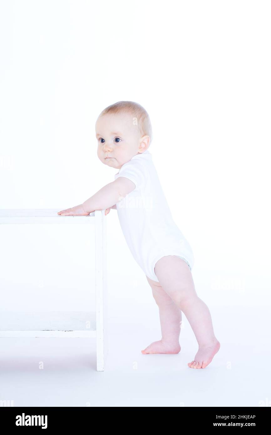 Baby boy standing holding on to shelf for support Stock Photo - Alamy