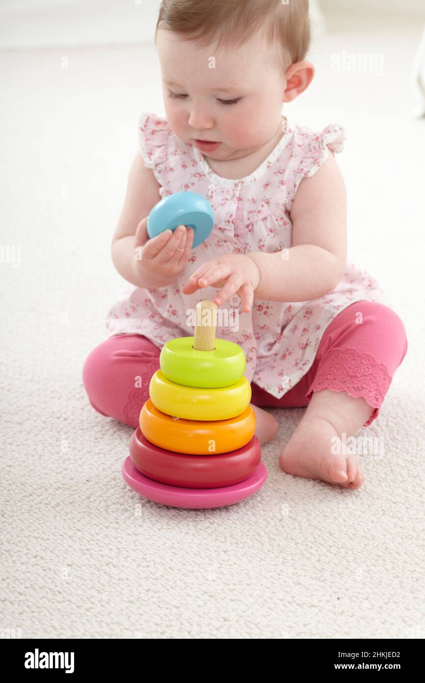 Baby girl sitting on floor playing with stacking rings Stock Photo - Alamy