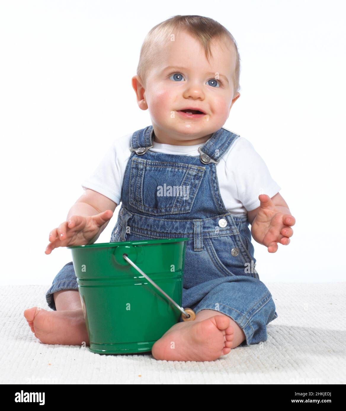 Baby boy sitting on floor with green bucket between legs Stock Photo ...