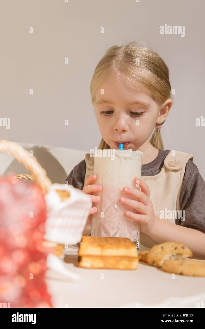 Cute little girl eating cookies with milkshake Stock Photo - Alamy