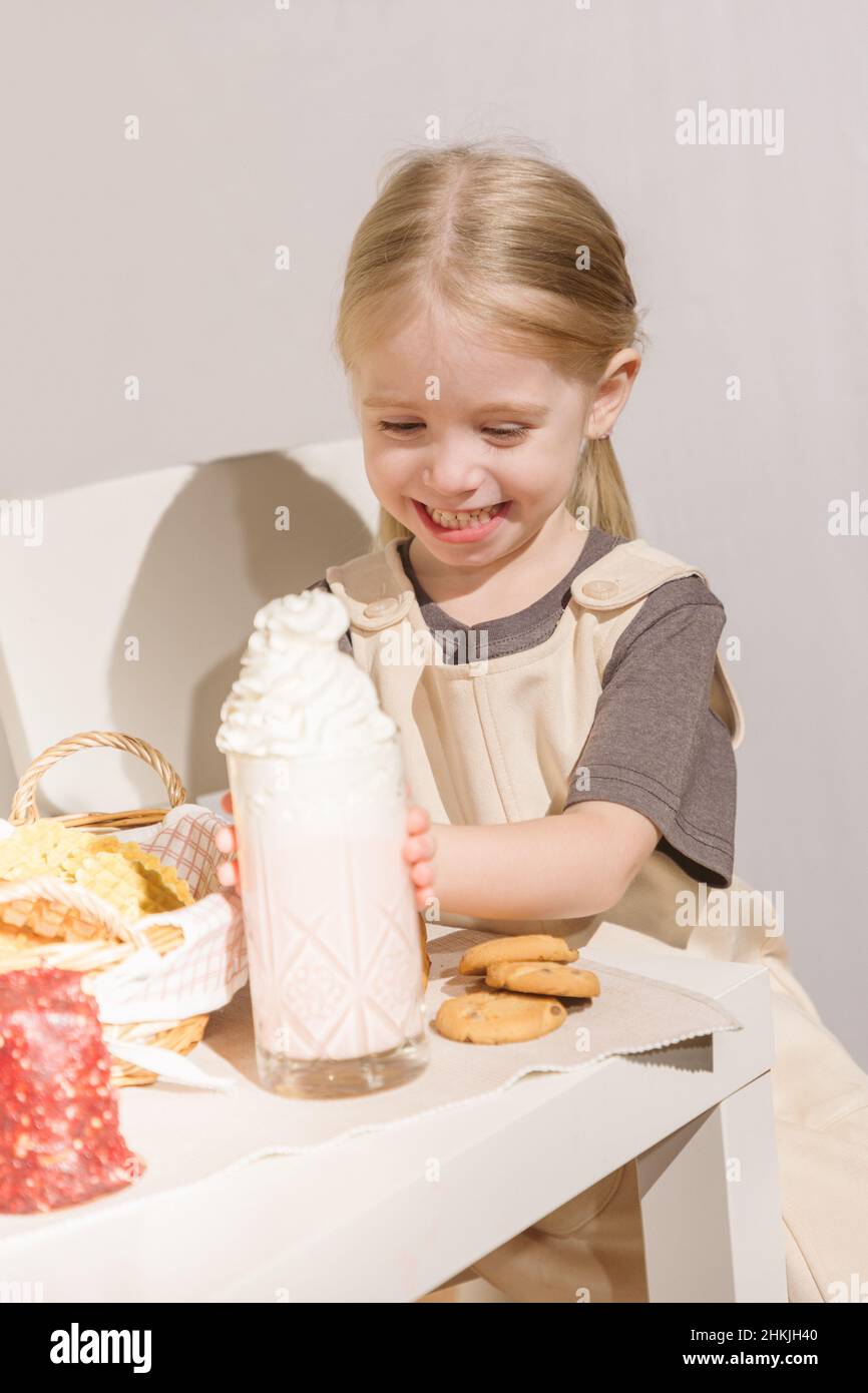 Cute little girl eating cookies with milkshake Stock Photo - Alamy