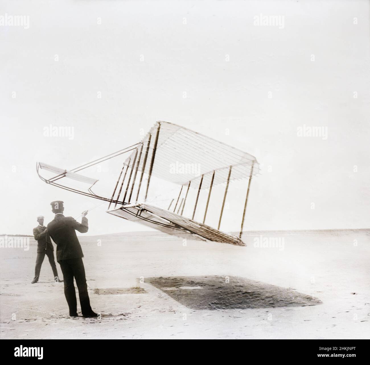 Side view of glider flying as kite near ground, Wilbur at left, Orville ...