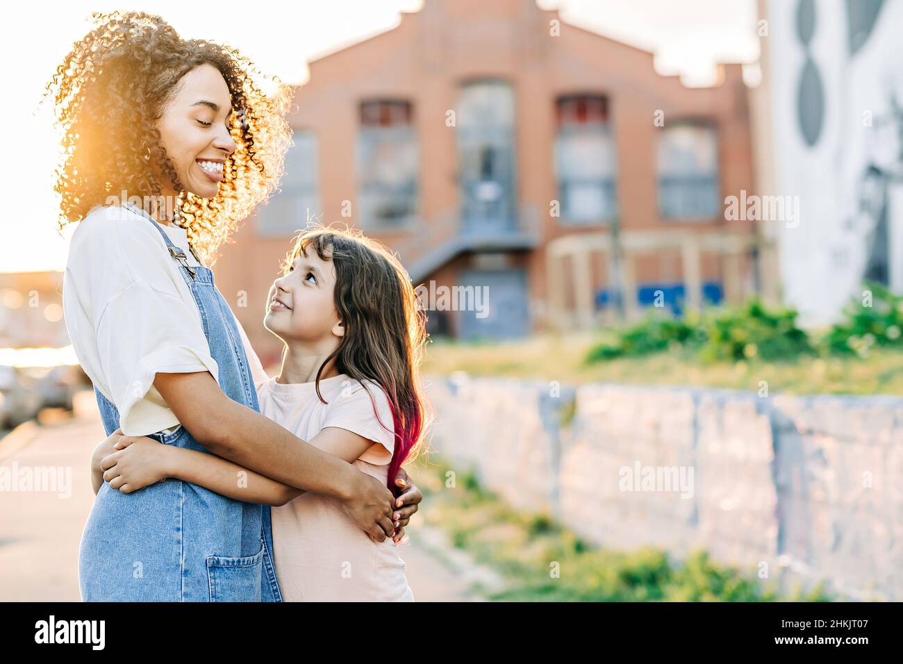 Happy child and babysitter smiling and hugging in sun lights outdoor ...