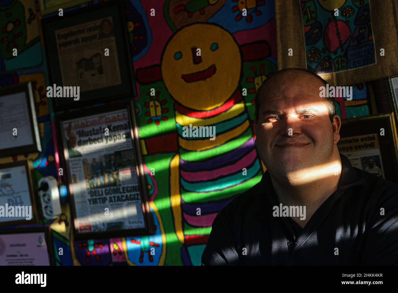 Muhammed poses in their living room next to a drawing on the wall ...