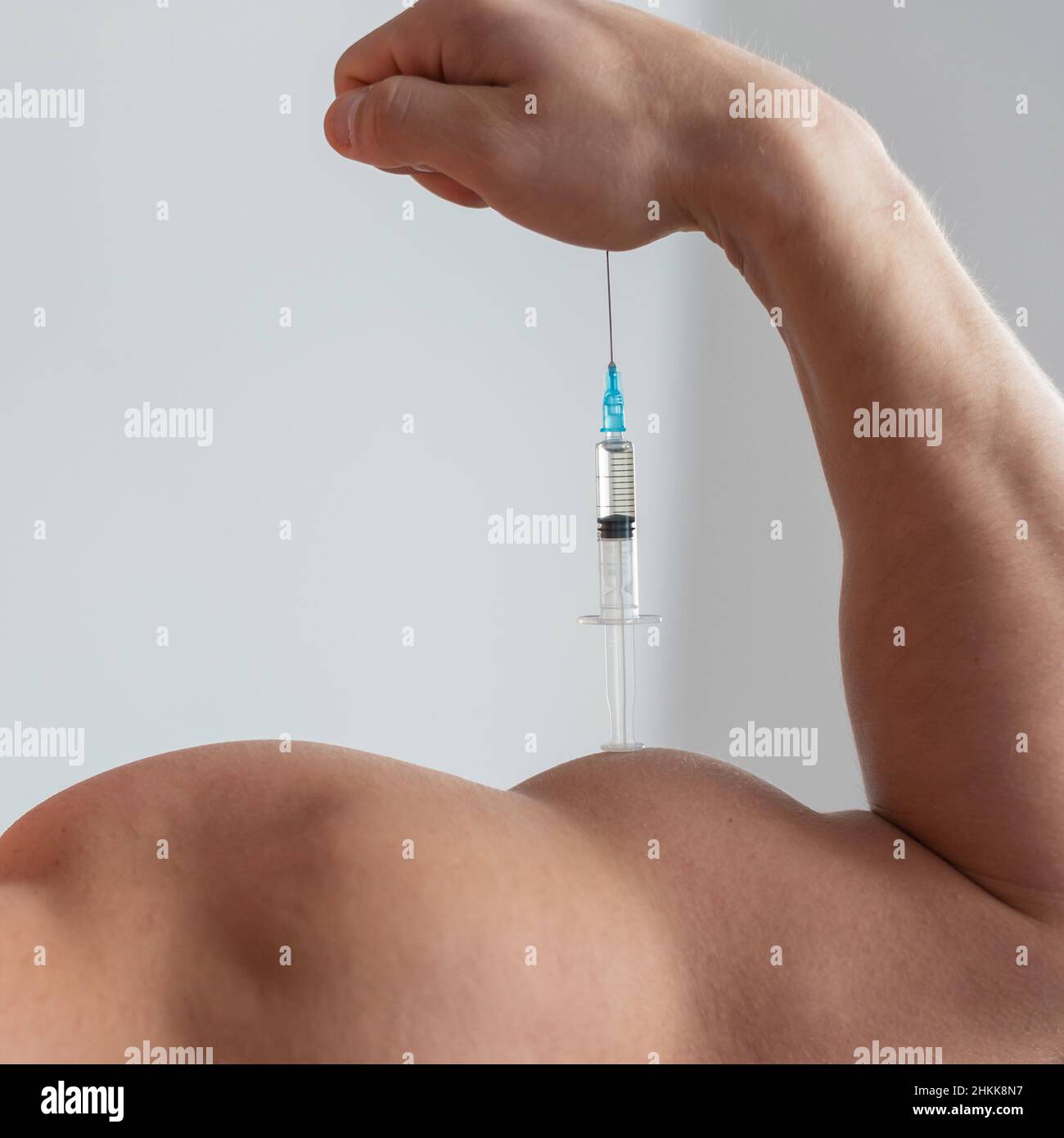 Closeup of a male hand with a dope syringe. Cropped biceps of a man ...