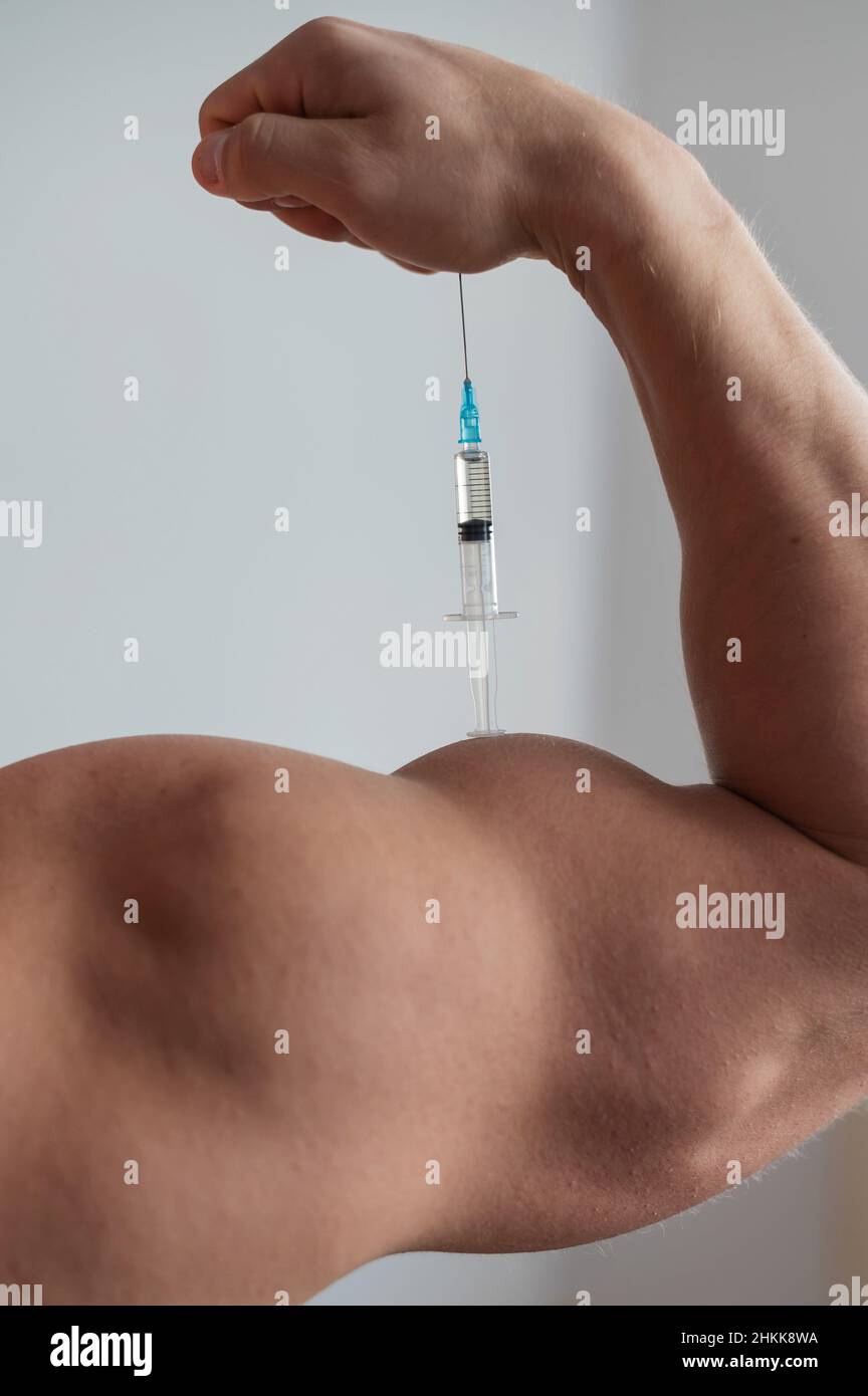 Closeup of a male hand with a dope syringe. Cropped biceps of a man ...