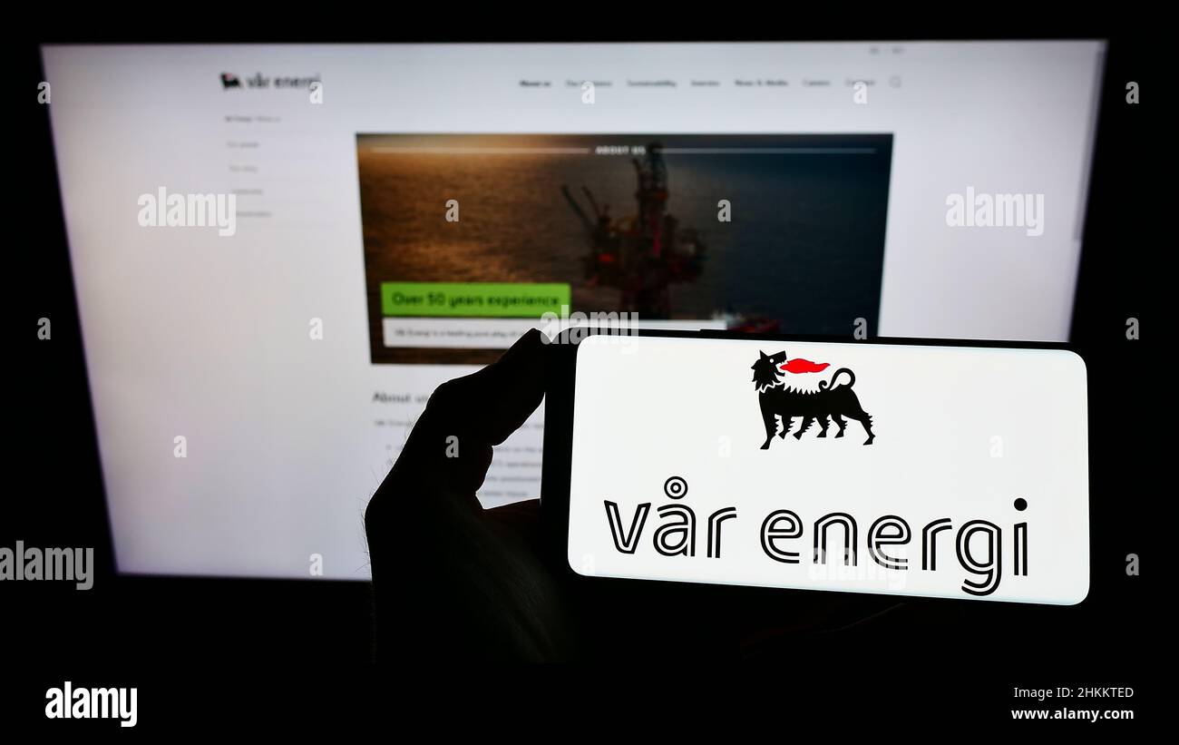 Person holding mobile phone with logo of Norwegian oil and gas company ...