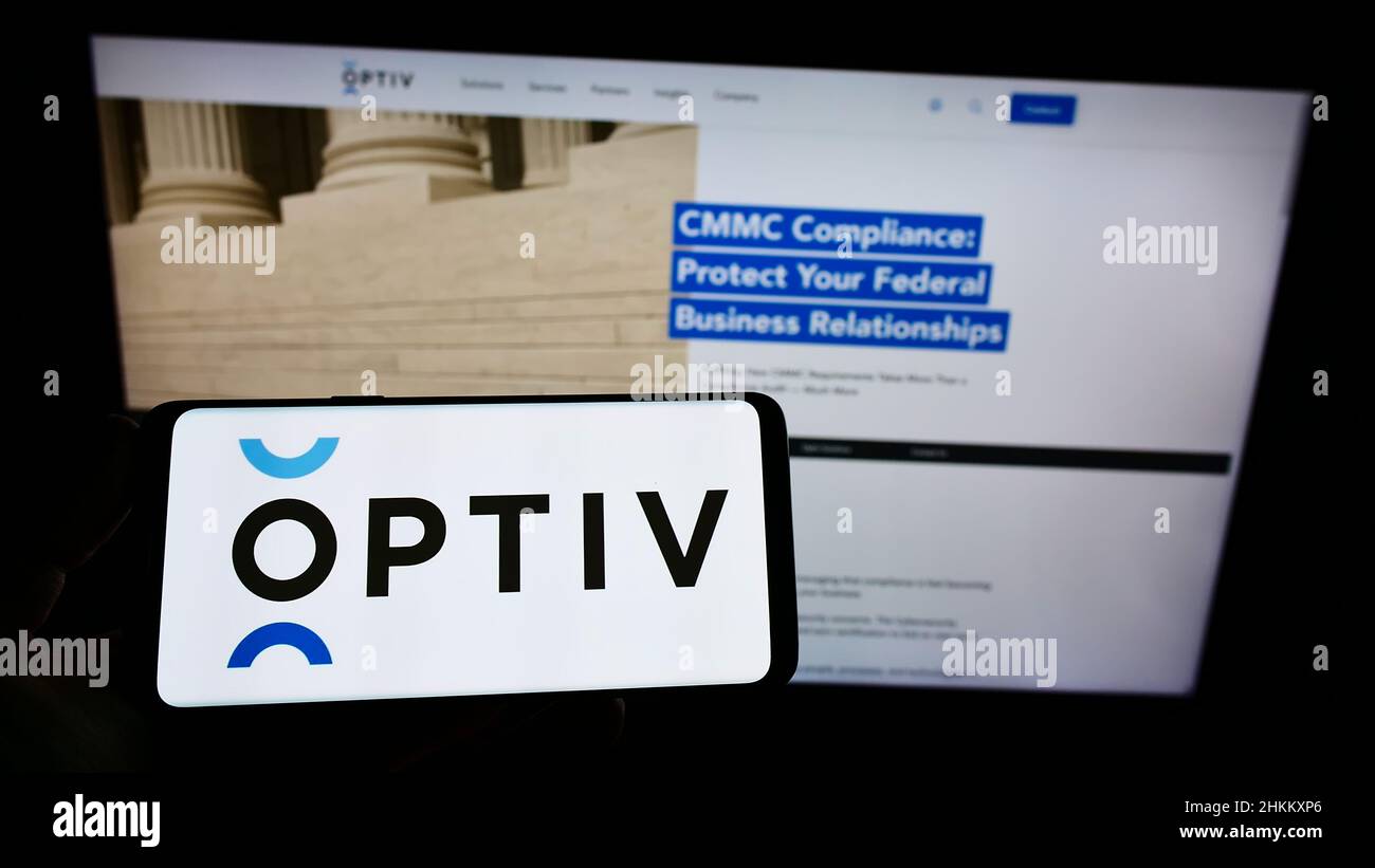 Person holding smartphone with logo of US company Optiv Security Inc. on screen in front of ...