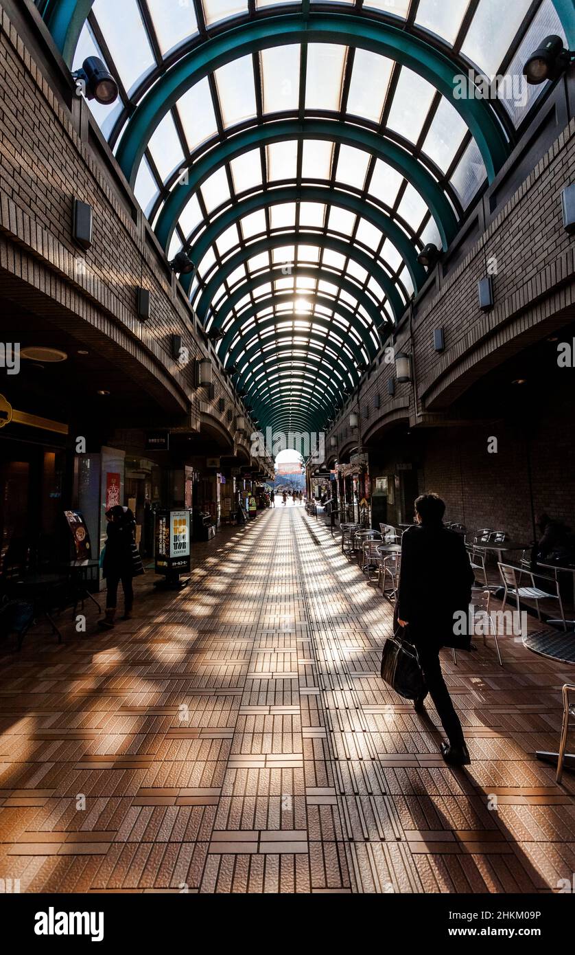 A Japanese male office worker or salaryman walks through an arched ...