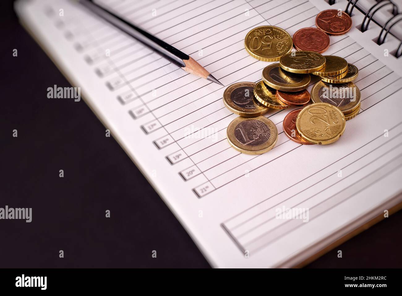 coins and pencil and notebook on a black background Stock Photo - Alamy