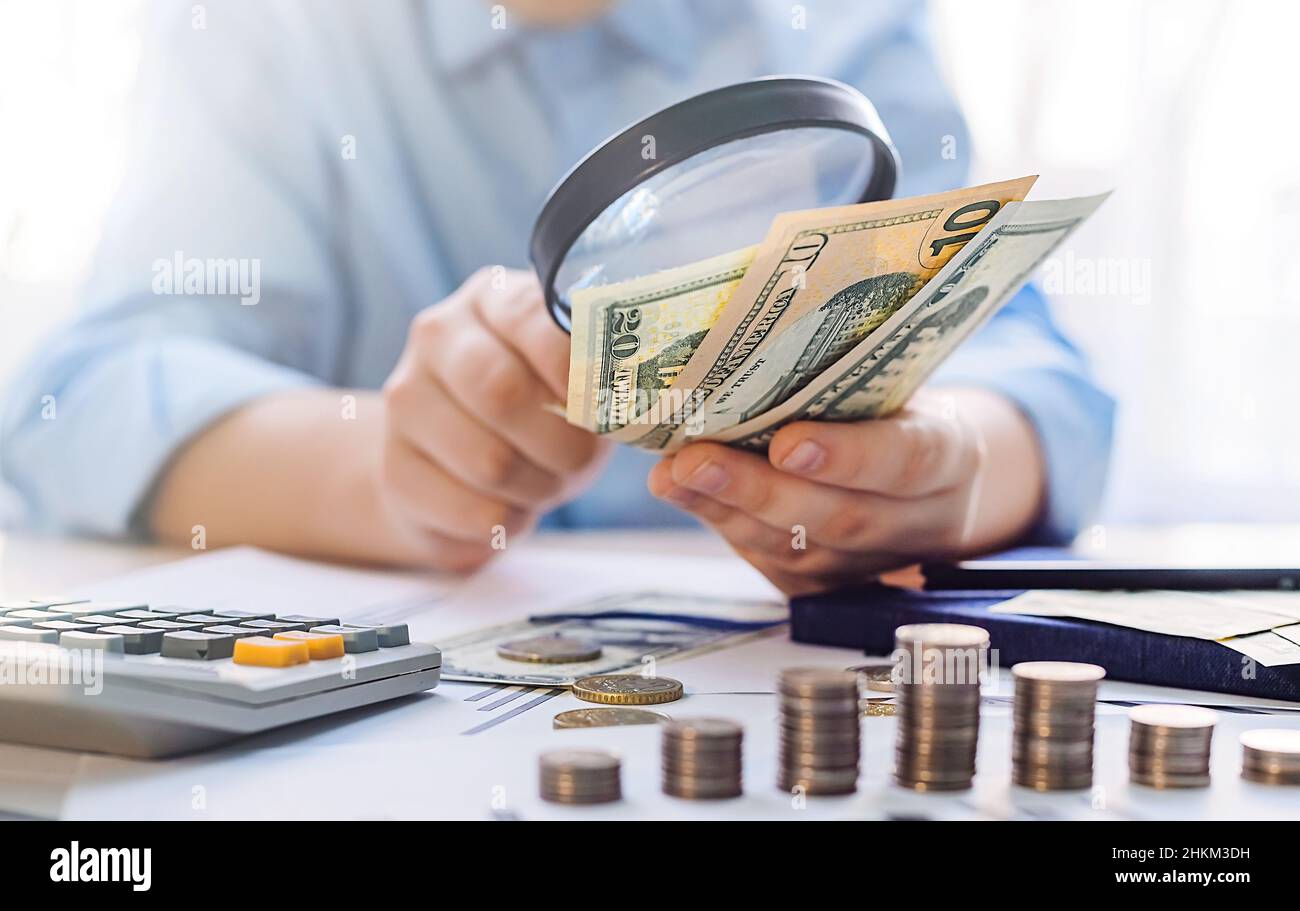 A man examines money through a magnifying glass. Dollars under a ...