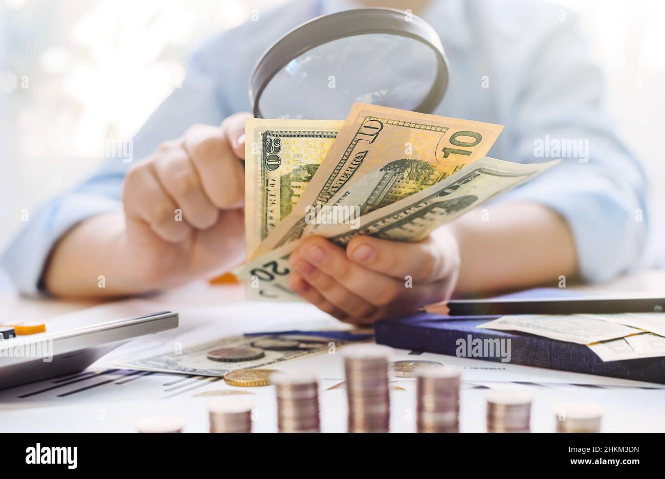 A man examines money through a magnifying glass. Dollars under a ...