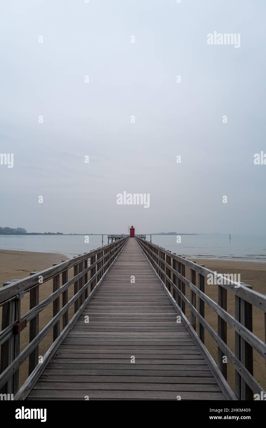 Small red old lighthouse at the end of a long jetty from a high ...