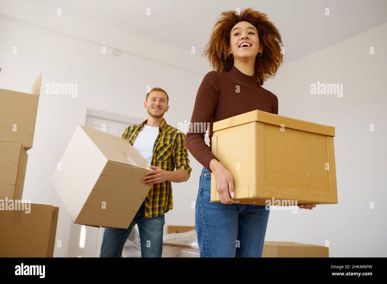 Happy multiethnic couple carrying cardboard box together Stock Photo ...